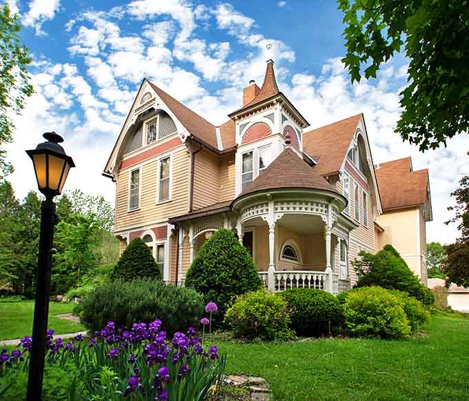 Spring announces itself with purple iris sentinels standing guard around a Victorian masterpiece that wears its architectural details like fine jewelry.