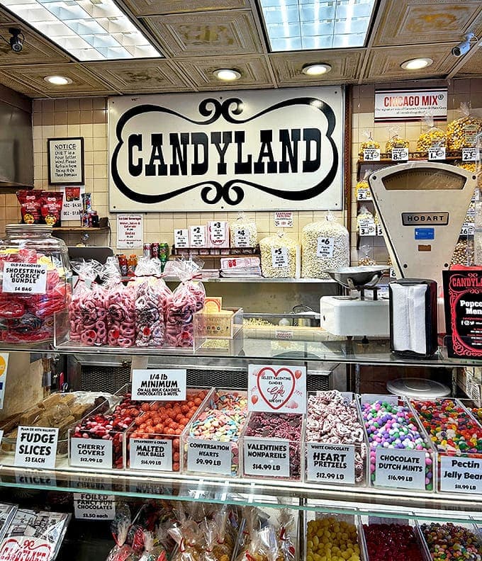The main counter showcases an array of fudge slices, conversation hearts, and other treats arranged with the precision of a sugar-based art installation.