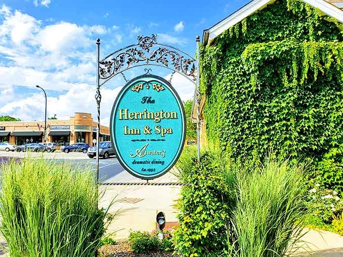 The Herrington's elegant entrance sign stands amid ornamental grasses, promising romantic dining and spa indulgences beyond its ivy-covered walls.
