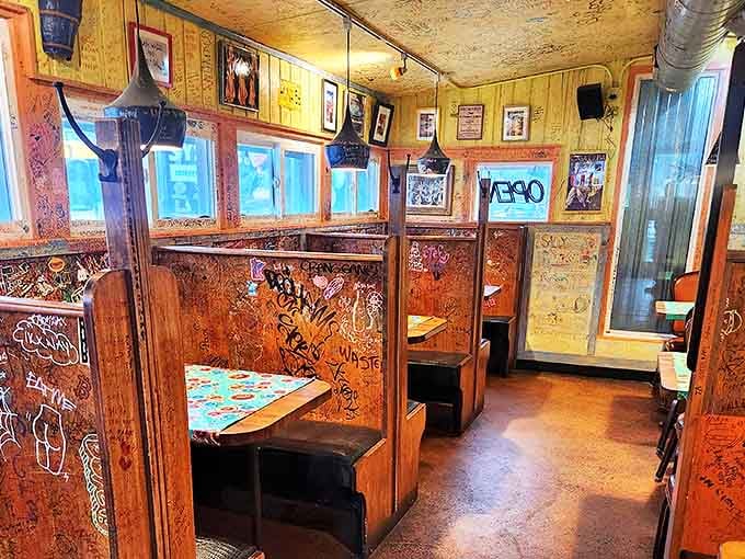 Cozy wooden booths covered in years of colorful messages create dining nooks that feel both private and part of something bigger.