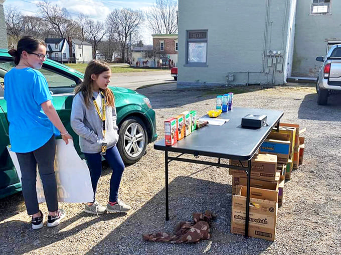 Future cardboard boat captains contemplate their designs. The serious expressions suggest they're calculating exactly how long until they're swimming instead of sailing.