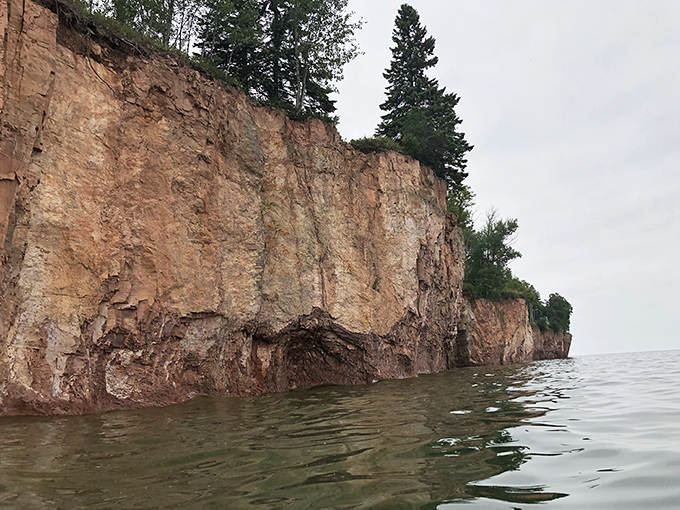 Ancient volcanic cliffs stand sentinel over the beach, slowly surrendering their pink rhyolite to Lake Superior's persistent waves.