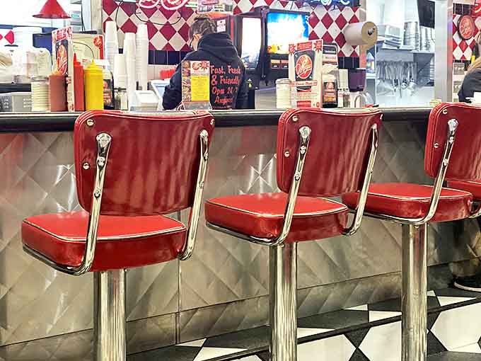 Red-topped stools line the counter, inviting customers to take a front-row seat to the culinary theater of hot dog preparation.