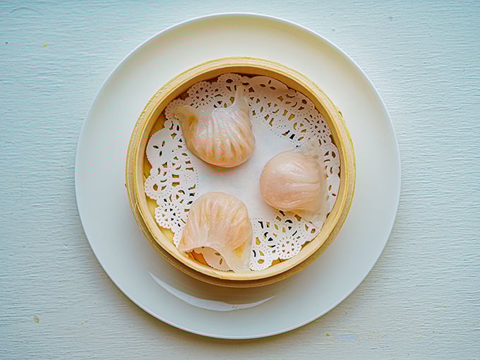 Delicate dim sum dumplings sit like little treasures in their bamboo steamer, their translucent skins revealing the delicate morsels waiting inside.