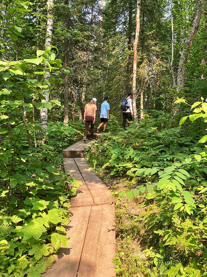 Fellow hikers traverse the wooden boardwalk, scale providing perspective on just how intimate this wilderness experience feels despite its grandeur.