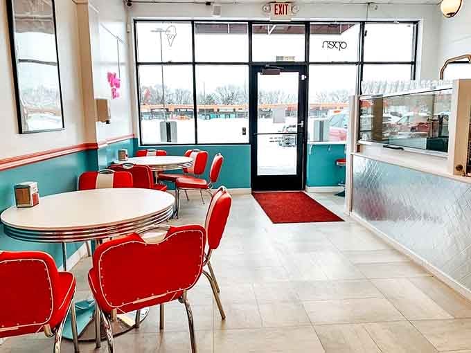 Retro-modern perfection with turquoise walls, cherry-red seating, and a doorway that promises even more delights beyond.