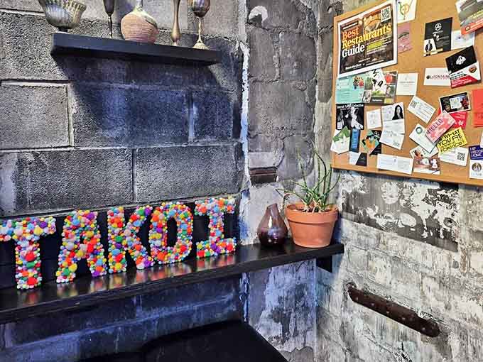 Colorful pom-poms spell out "TAKOI" against exposed brick &ndash; industrial chic meets playful whimsy in this thoughtfully designed space.