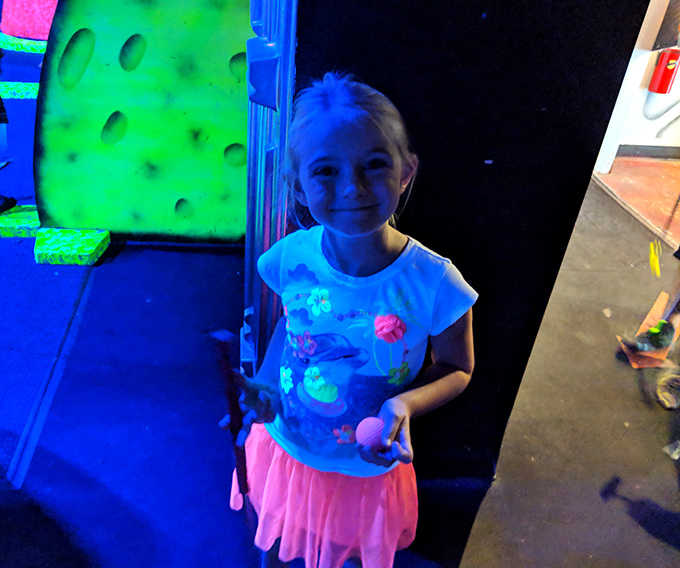 The blacklight brings everything to life, including this young explorer's outfit. That smile says it all: space adventures beat regular mini-golf any day!