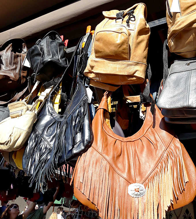 Leather bags hang like ripened fruit, each one hand-tooled and fringed to perfection &ndash; wearable art with stories stitched into every seam.