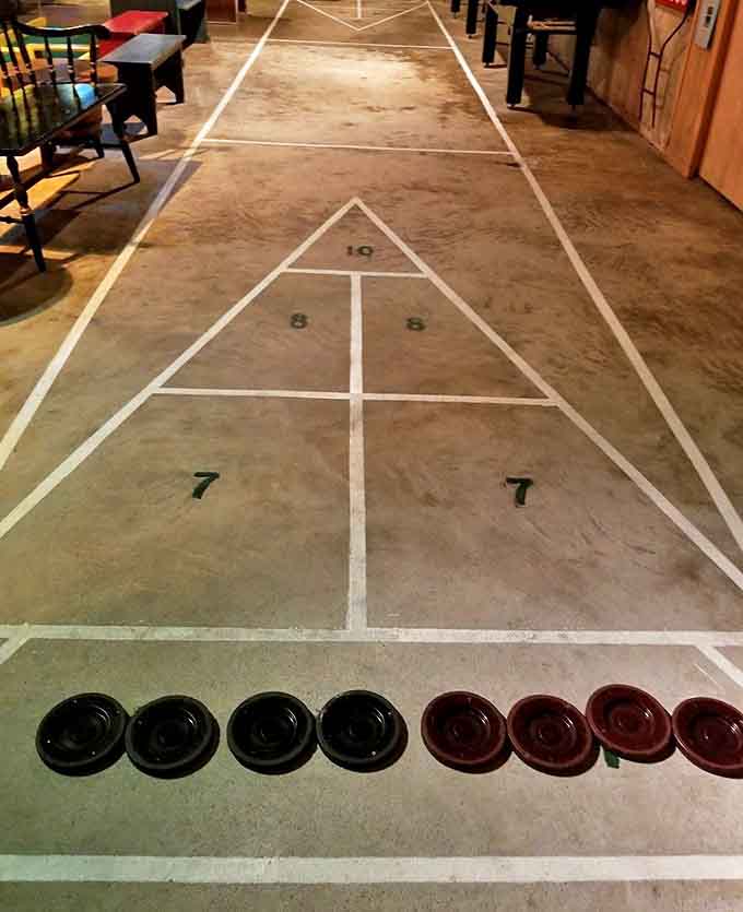 A regulation shuffleboard court proves this community room takes its entertainment seriously, even when surrounded by skeletons.