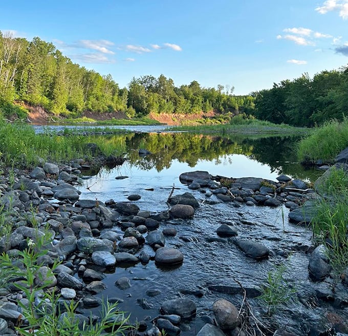 The river's calm pools reflect the sky, creating mirror images of Minnesota's natural beauty.