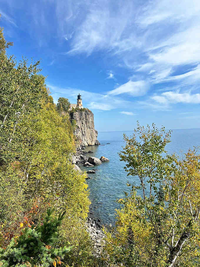 Framed by vibrant foliage, the lighthouse appears almost like a painting come to life. This view explains why artists and photographers have been drawn here for generations.