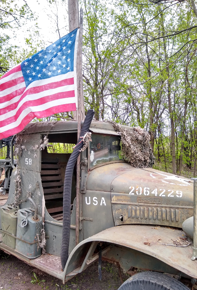 This vintage military truck stands at attention, its American flag still proudly waving &ndash; history parked right before your eyes.