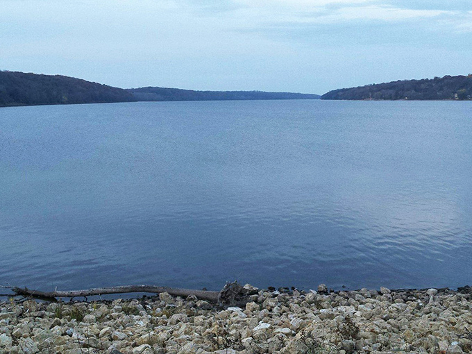 Tranquil waters mirror the sky's mood, cradled between forested bluffs that have watched centuries of human drama unfold.