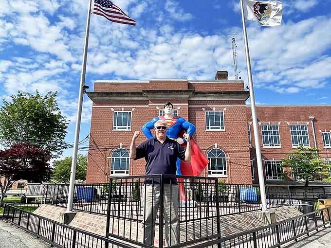 A visitor poses with the statue, demonstrating the perfect size comparison that makes this 15-foot Superman truly feel larger than life.