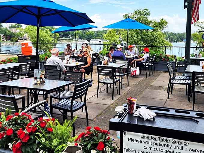 The outdoor patio strikes that perfect balance between sun and shade, with bright blue umbrellas creating comfortable oases for enjoying Michigan's fleeting summer days.