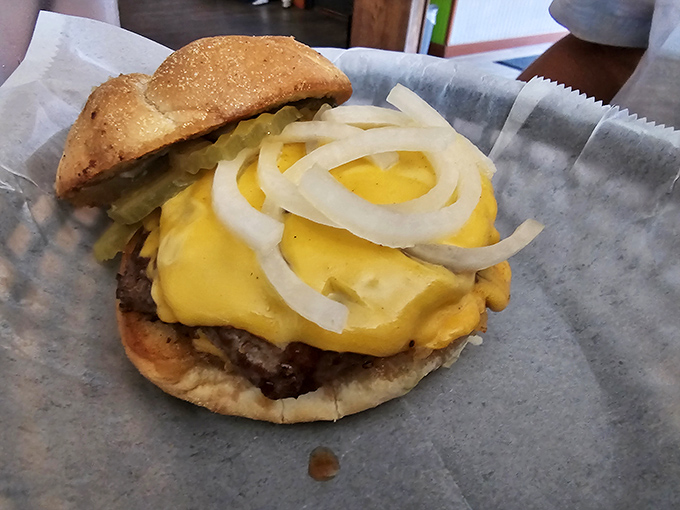 A juicy cheeseburger piled with melted cheese, crisp onions, and pickles, looking deliciously simple and ready to enjoy today now.