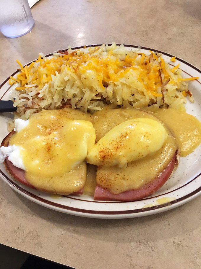 Eggs Benedict with hash browns &ndash; hollandaise cascading like a yellow waterfall over perfectly poached eggs and Canadian bacon.