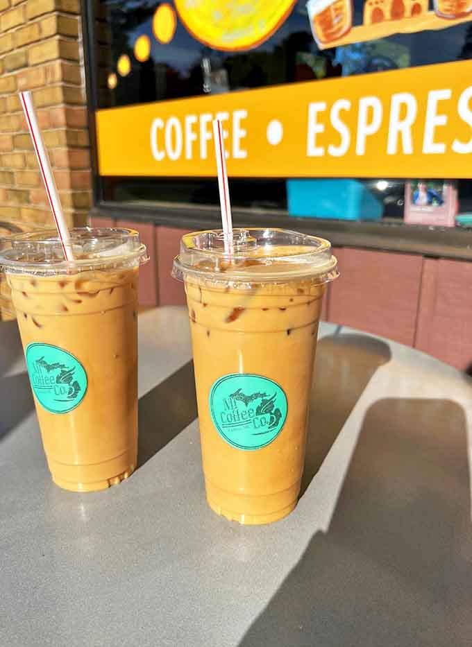 Twin iced lattes catching the sunlight like liquid amber &ndash; summer in Michigan distilled into perfectly proportioned cups of caffeinated bliss.