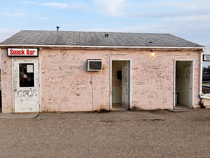 The pink snack bar building wears decades of visitor signatures like badges of honor, each scribble a memory made under the stars.