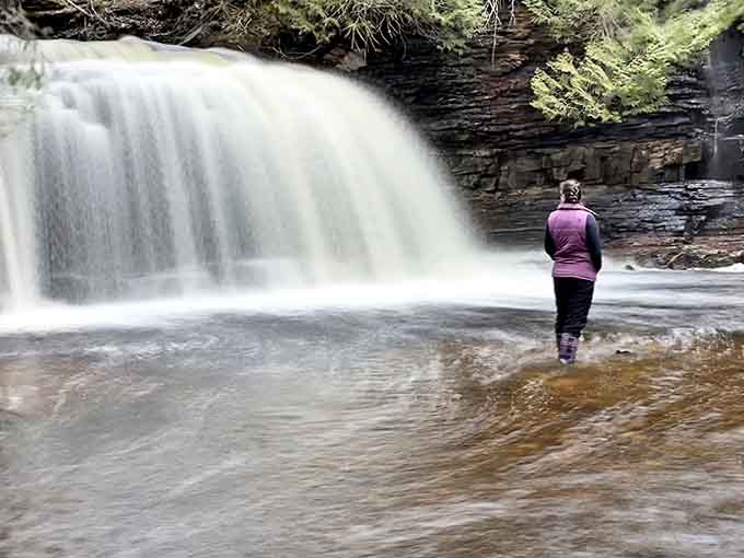 A moment of quiet contemplation as a visitor stands before the falls, experiencing the perfect ratio of human to nature that puts everything in perspective.