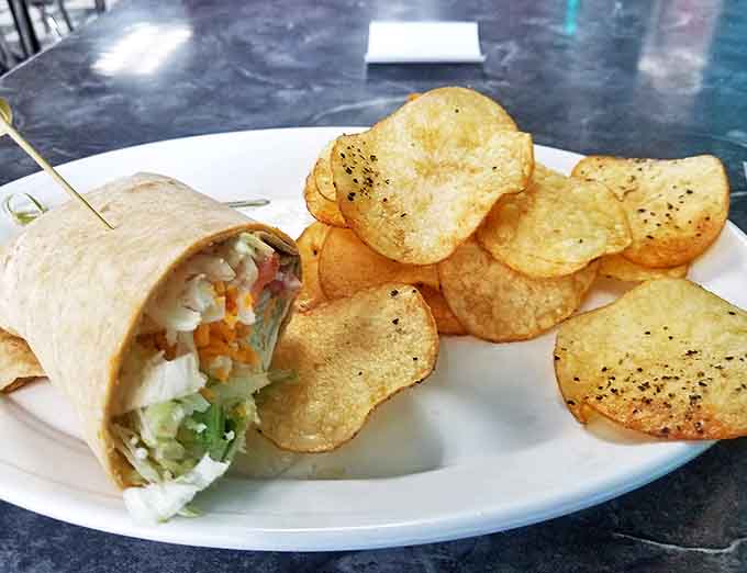 The veggie wrap brings California sunshine to Michigan winters, with crisp vegetables nestled in a tortilla blanket beside homemade chips.