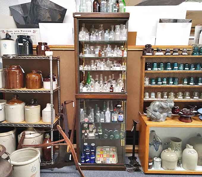 Vintage bottles line these shelves like soldiers at attention, from humble medicine containers to elegant decanters that once graced formal dining rooms.