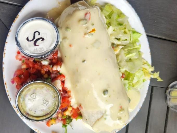 A sauce-draped burrito flanked by fresh pico de gallo and crisp lettuce creates the perfect balance of rich and refreshing.