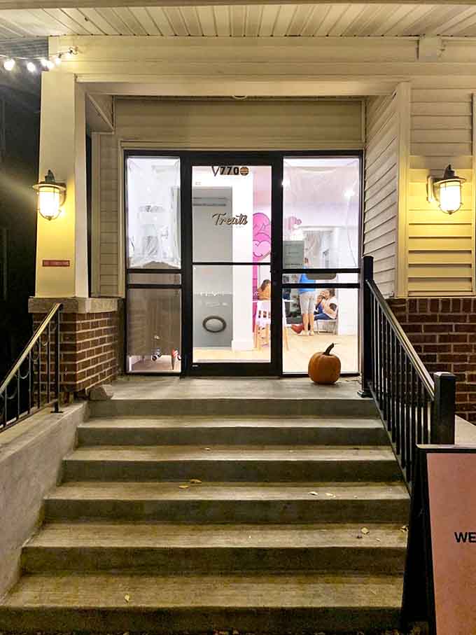 Evening visitors are greeted by warm lighting that transforms the simple entrance into a beacon of sweet possibilities ahead.