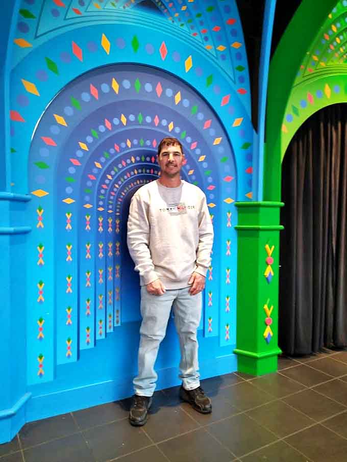 A visitor pauses for a photo opportunity, unaware his image will soon be multiplied infinitely inside the reflective labyrinth.