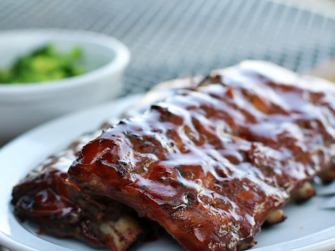 Glistening ribs painted with sauce that captures light like stained glass &ndash; barbecue as art form, ready for your appreciation.