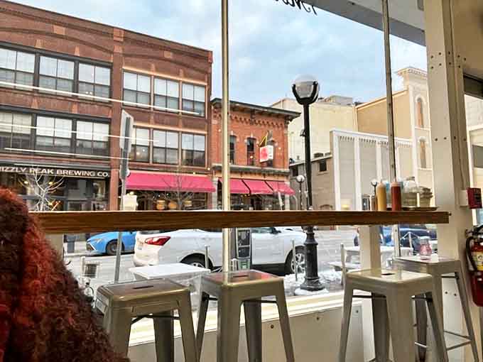 A window to Ann Arbor's bustling streets frames the minimalist interior, where food takes center stage against a backdrop of white brick.