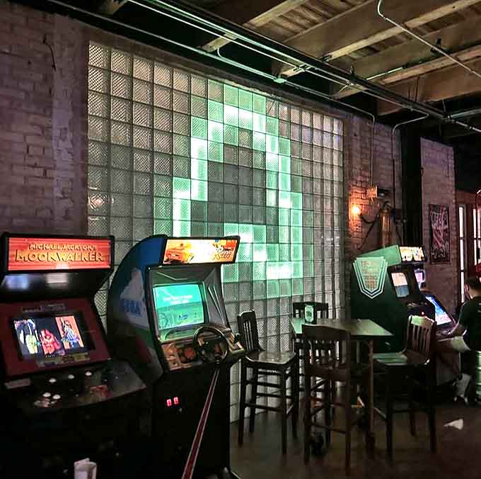 Vintage arcade cabinets line the walls, their screens flickering with familiar challenges. No quarters needed &ndash; just grab your drink and play.