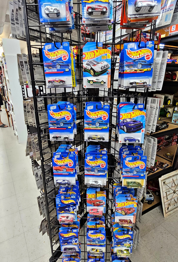 Hot Wheels cars in original packaging create a miniature time capsule of automotive dreams, each tiny vehicle carrying oversized nostalgia for Saturday morning cartoon commercials.
