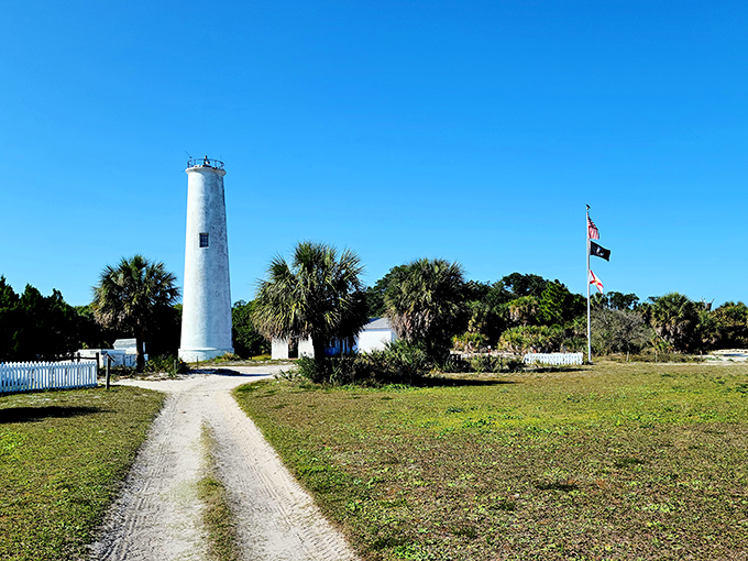 The lighthouse stands as a steadfast guardian, surrounded by palm trees swaying in the gentle Gulf breeze.
