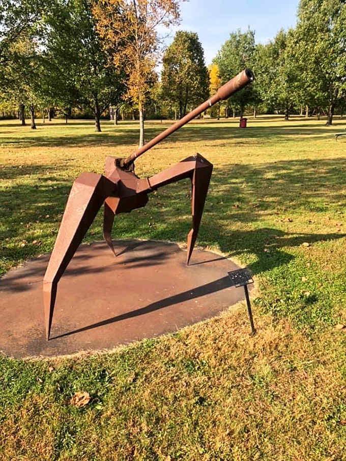 An abstract sculpture in rich rust tones seems to dance across its concrete base, frozen mid-movement like a performer taking a final bow.