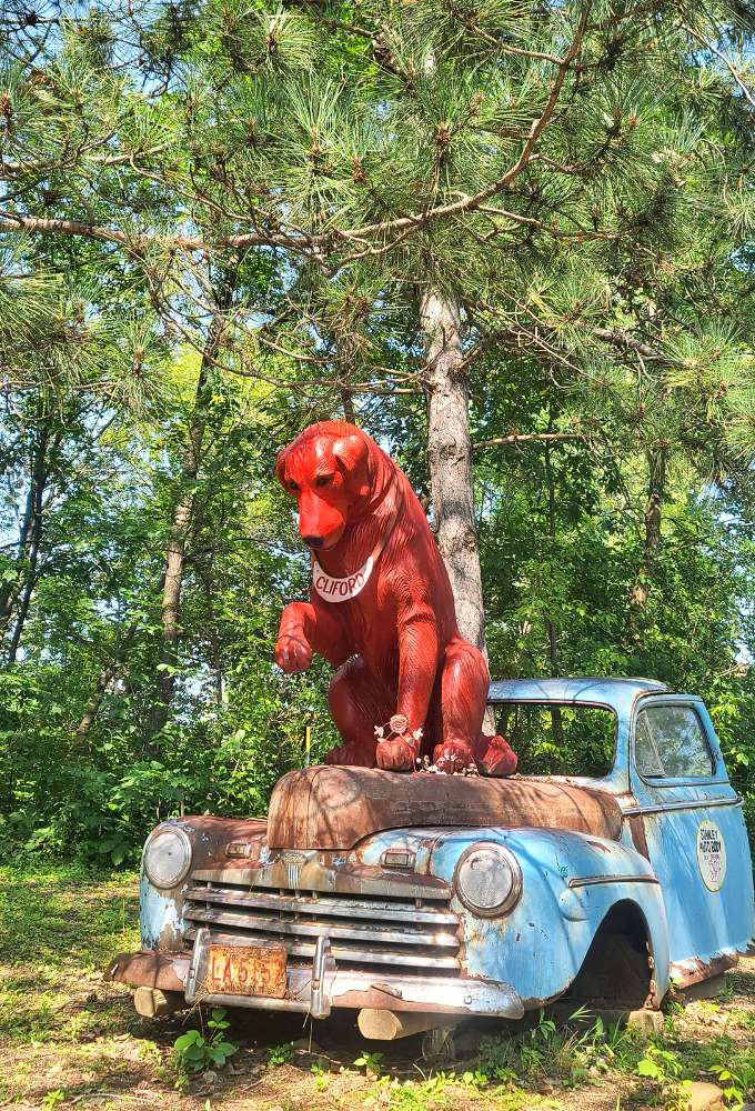 This bright red dog perched atop a vintage truck proves that even rusty sculptures can be man's best friend.