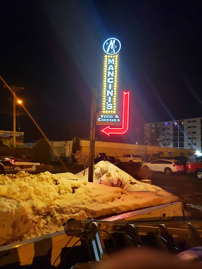 Mancini's neon sign glows against the night sky &ndash; a beacon for hungry travelers and locals seeking steakhouse perfection.
