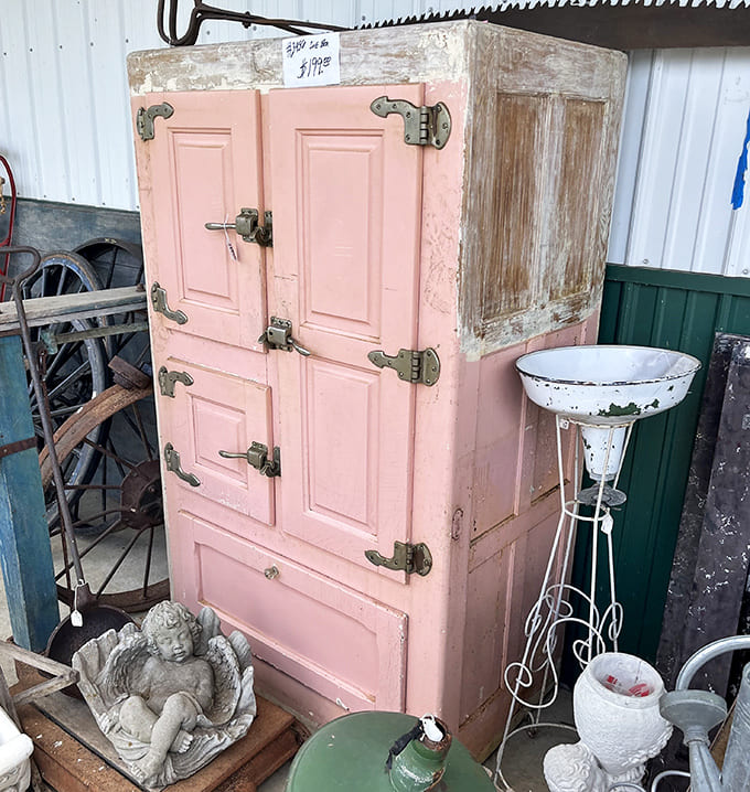 A perfectly pink vintage cabinet sits outside among garden treasures, its pastel hue and sturdy construction representing an era when even iceboxes were designed to make a style statement.