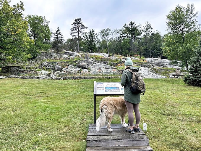 A visitor and canine companion pause to read about the gardens' history, the perfect starting point for appreciating the artistic vision behind these remarkable stone creations.