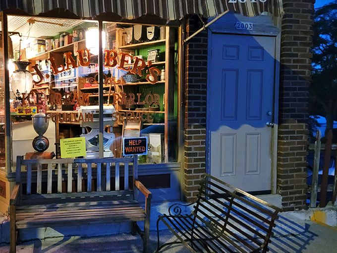 Evening brings a magical glow to this brick storefront, where benches invite contemplation and windows promise sweet rewards for anyone brave enough to venture inside.