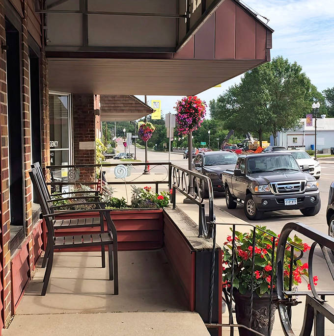 The covered porch area, adorned with cheerful flowers, offers front-row seats to small-town life unfolding at its own unhurried pace.