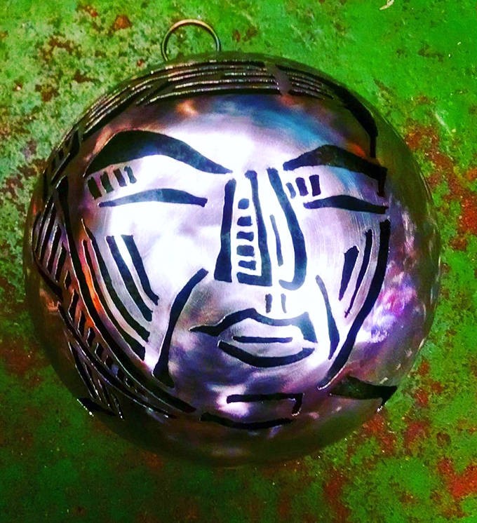 This circular metal face combines industrial techniques with artistic vision, creating an expression somewhere between serene and slightly surprised.