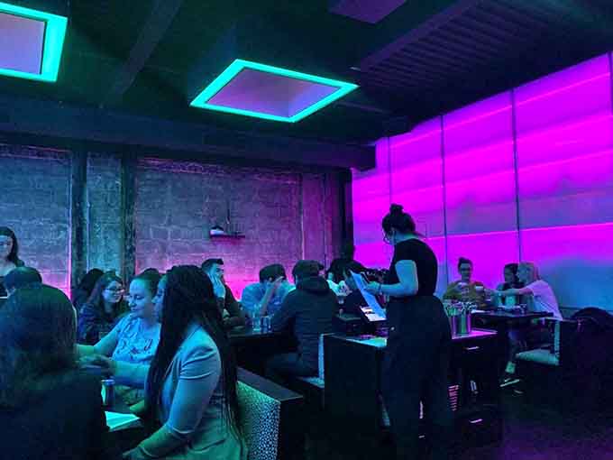 Diners bask in purple-hued ambiance, creating a dreamlike setting where conversations flow as freely as the cocktails.