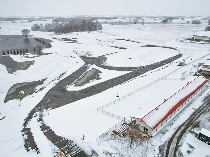 Even in winter's embrace, the track's outline remains visible, a sleeping giant waiting for spring's return to roar back to life.