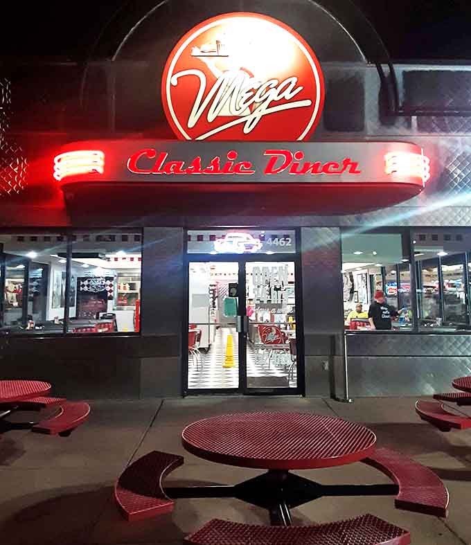 Night transforms the diner into a neon-lit promise of comfort, where the glowing sign beckons weary travelers with the siren song of milkshakes.