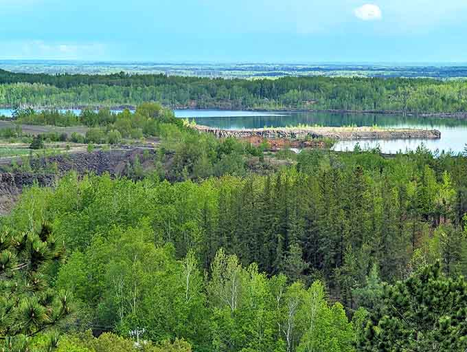 Spring's vibrant greens create a lush tapestry around the mine lake, nature's way of softening the industrial edges.