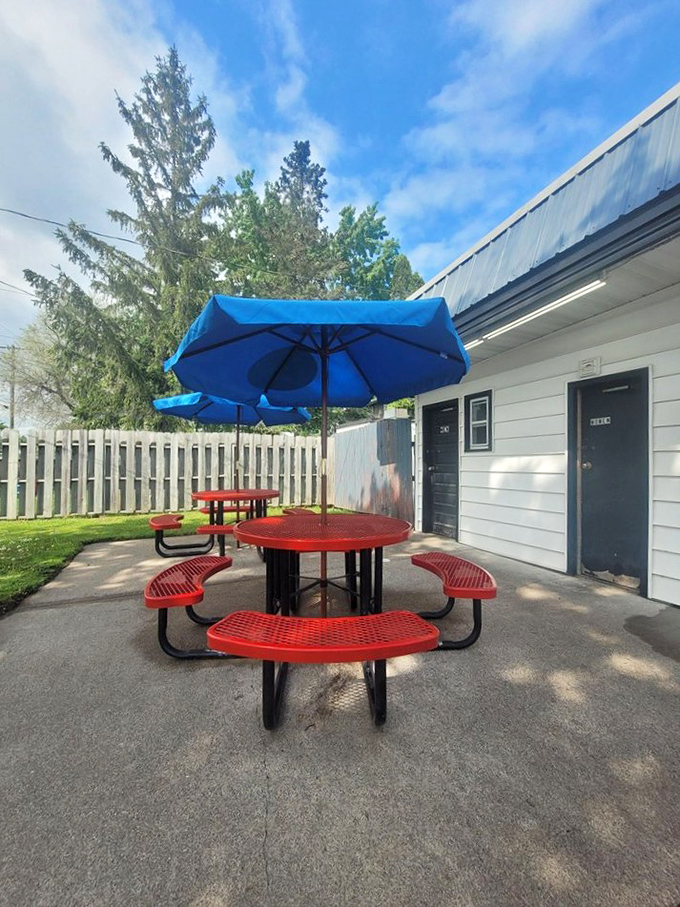Bright blue umbrellas provide shade for the cherry-red picnic tables, creating the perfect spot for savoring summer treats. 