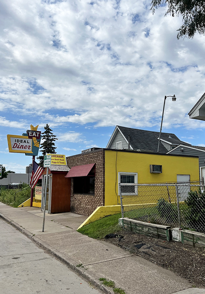 Sunshine bathes the yellow exterior, highlighting the diner's cheerful presence in the neighborhood it's served for generations.