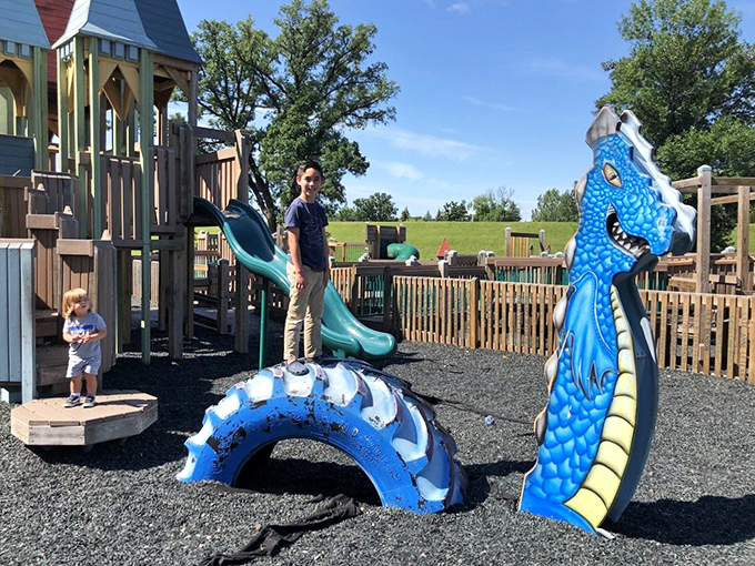 A blue dragon emerges from the playground surface, adding mythical elements to this already magical wooden kingdom.